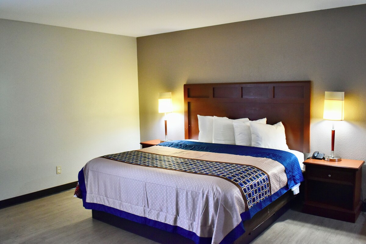 Quarto de hotel com uma cama, duas mesas de cabeceira e uma luminária.