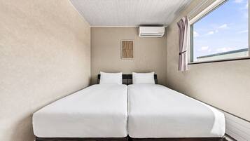 Quarto com cama, janela e ar condicionado.