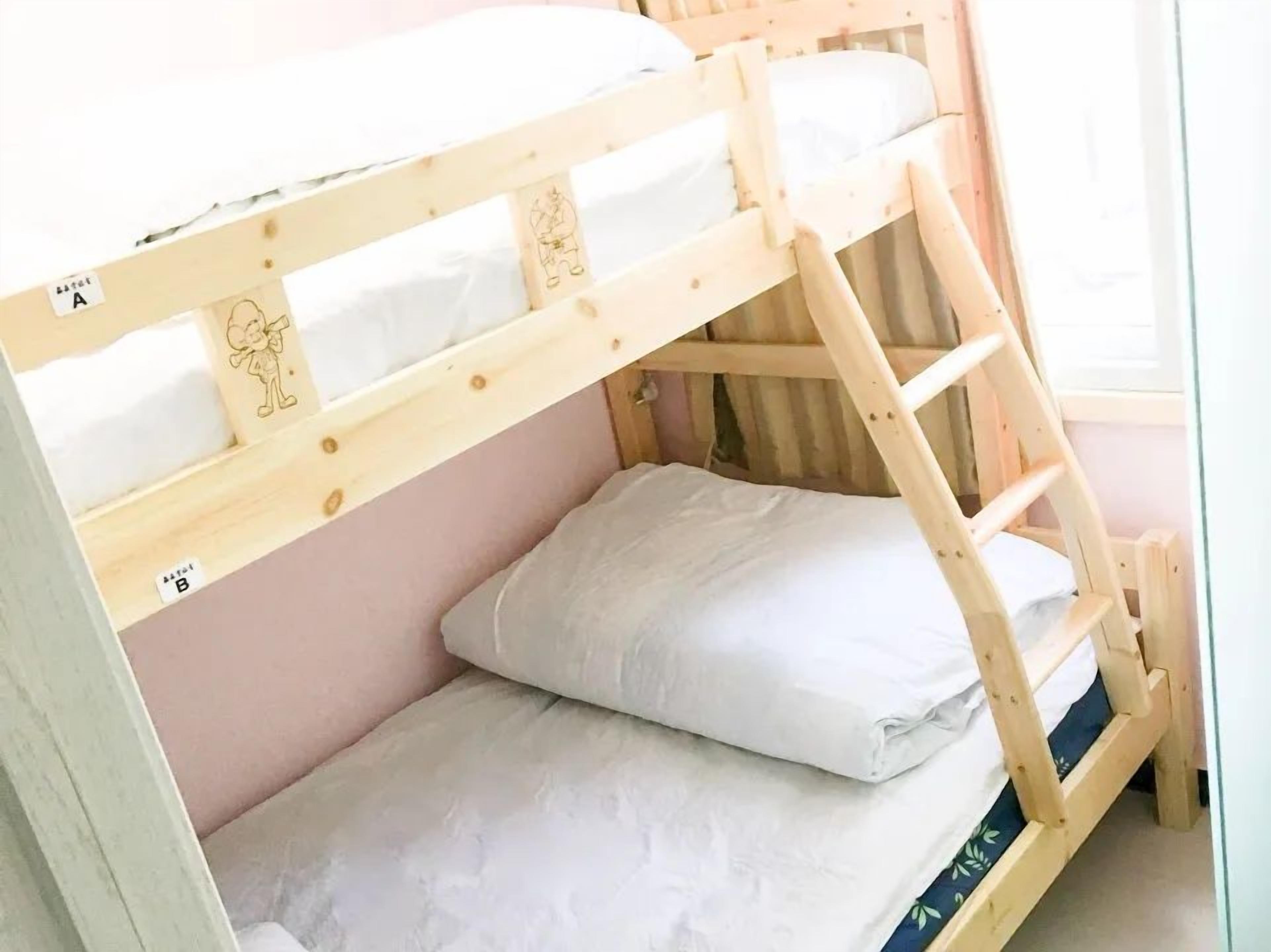 Uma cama beliche com escada, travesseiro e etiqueta lateral.