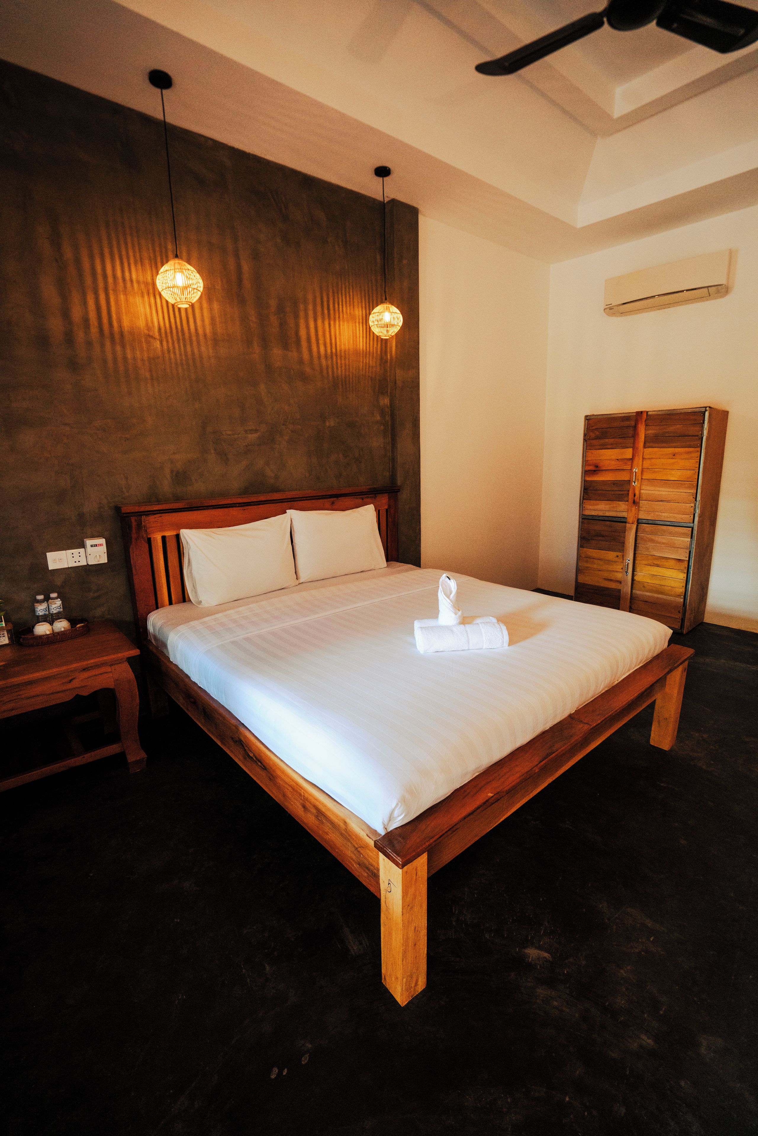 Quarto de hotel com cama grande, cabeceira de madeira, mesas de cabeceira e guarda-roupa.