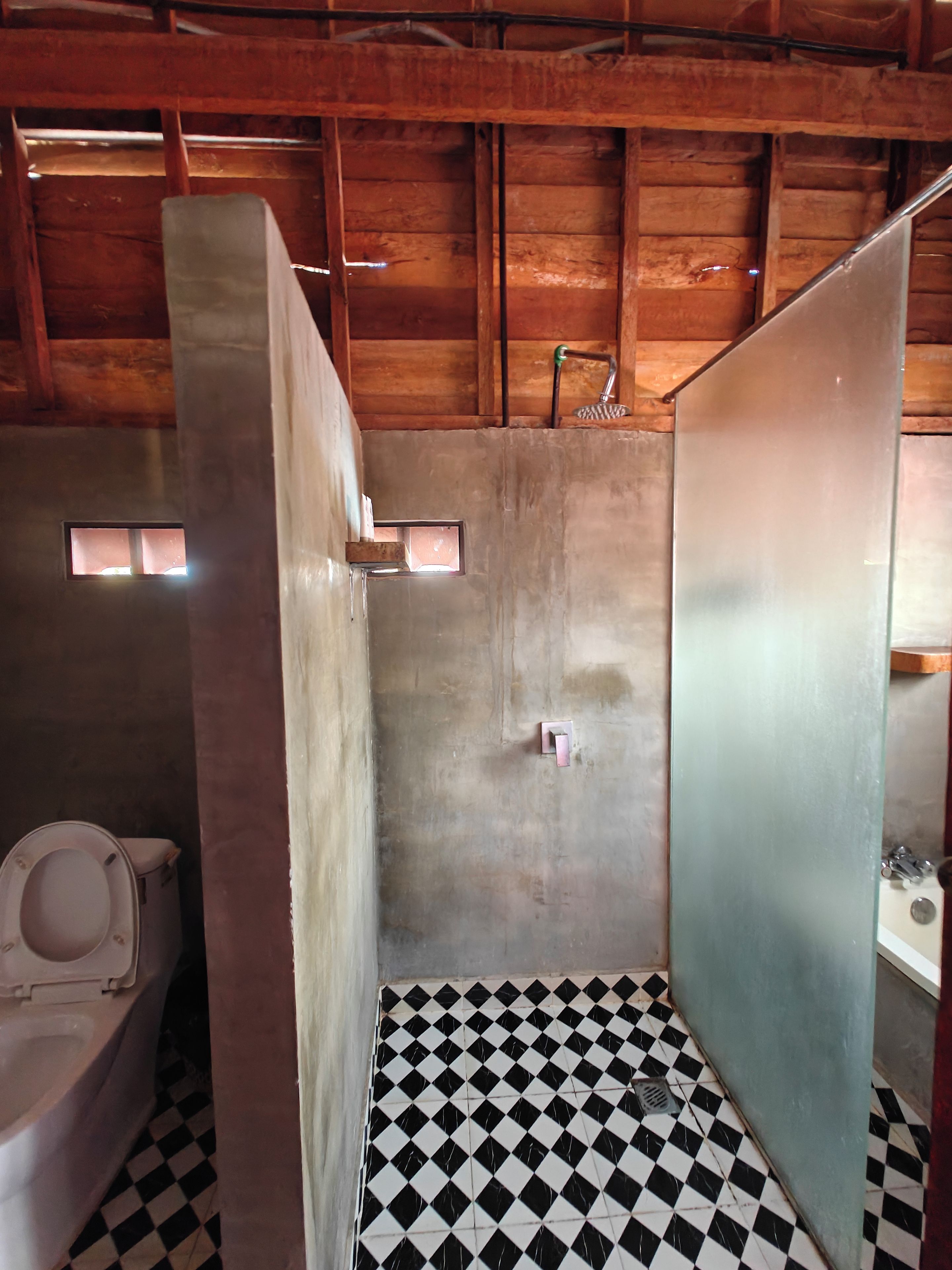 Casa de banho com chão xadrez, sanita e cabine de duche.