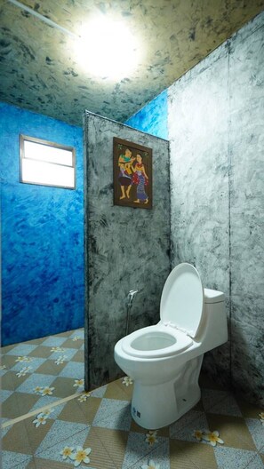 Casa de banho com sanita branca, cabine de duche e parede azul.