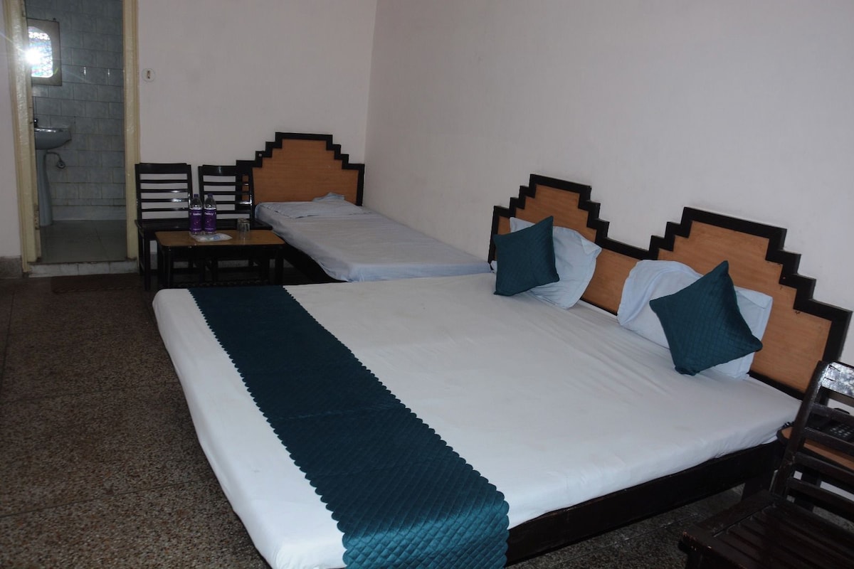 Quarto de hotel com duas camas, uma mesinha e uma cadeira.