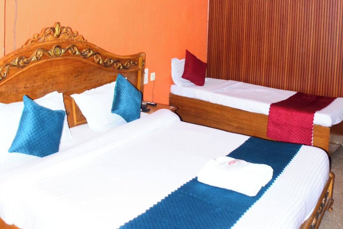 Quarto com cama, sofá, ventilador de teto e quadro na parede.