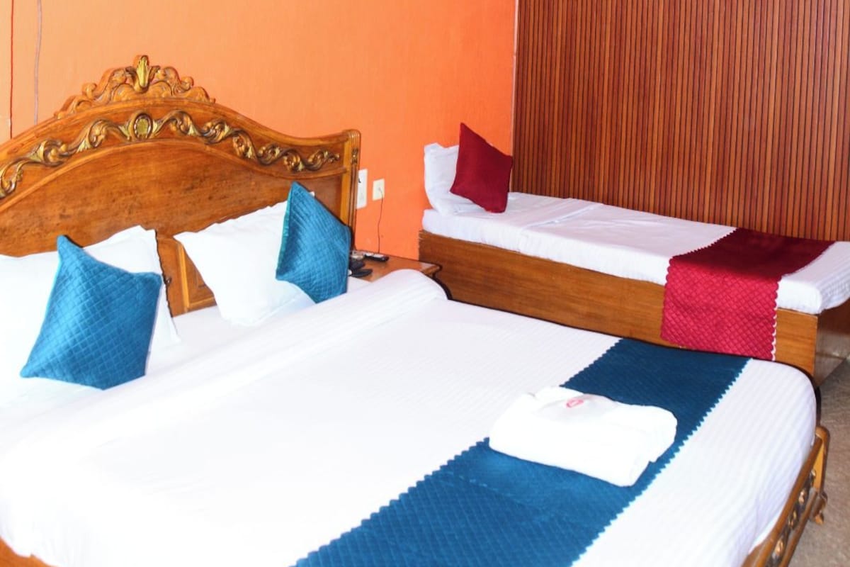 Quarto com cama, sofá, ventilador de teto e quadro na parede.