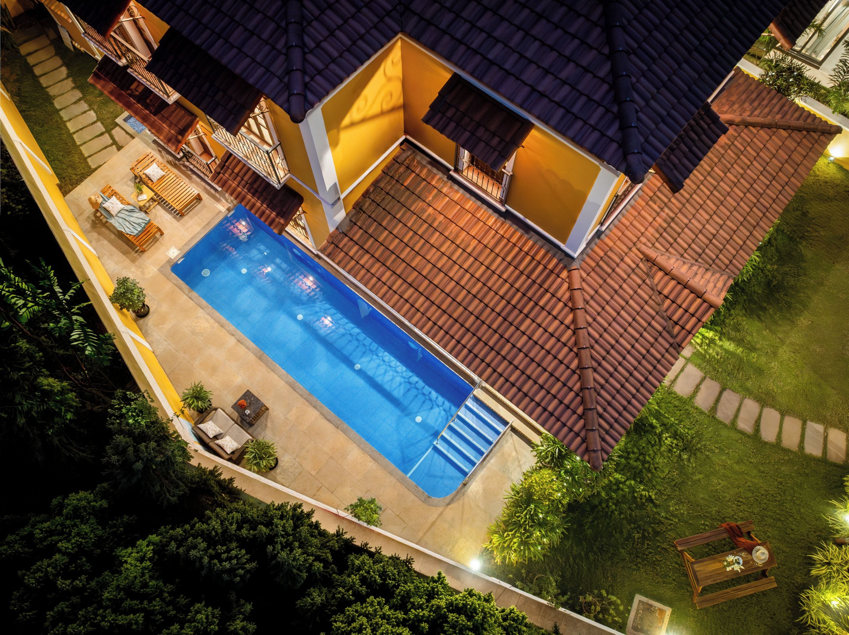 Uma piscina no terraço com um deck revestido ao redor, uma pequena área de estar e vista para os edifícios circundantes.