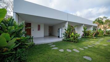 Uma casa moderna com telhado plano, varanda coberta e jardim bem cuidado com pedras no caminho.