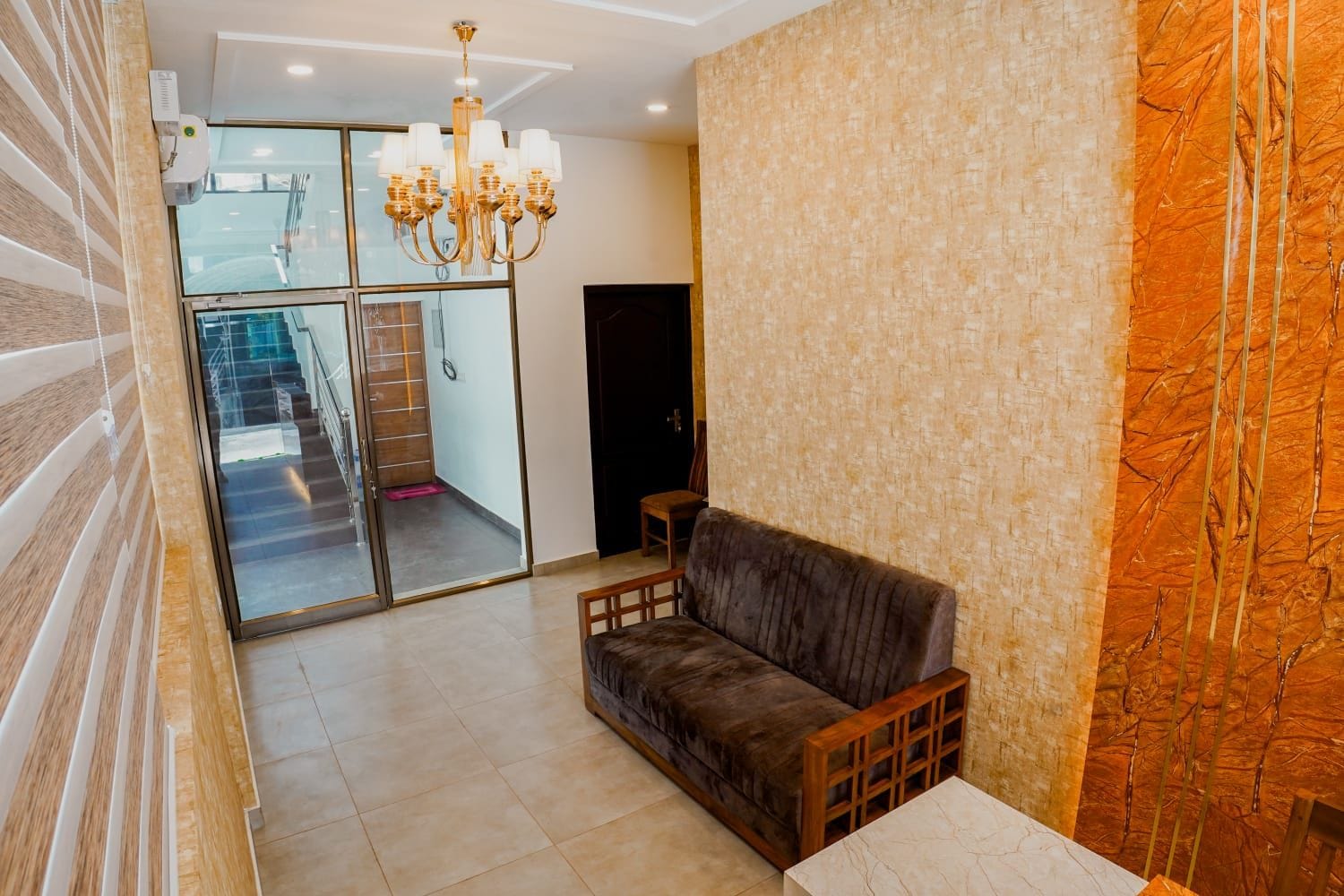 Um interior moderno com sofá, lustre e vista para uma escada que dá para outro cômodo.