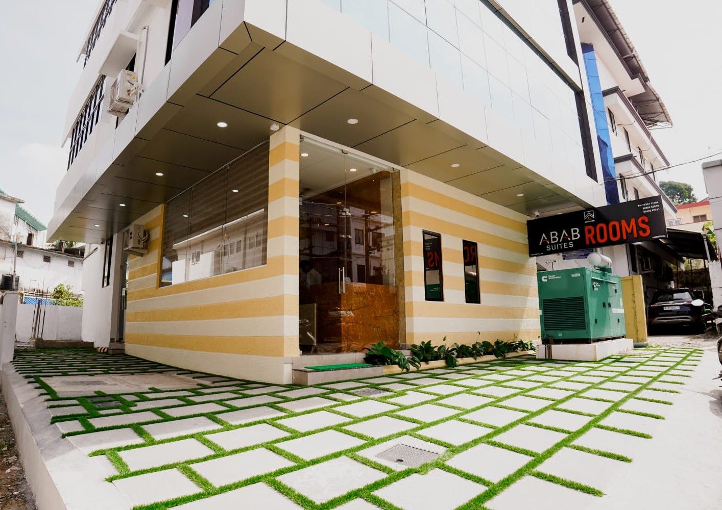 Um hotel com fachada moderna, entrada coberta e uma placa indicando 'ABAB ROOMS' para suítes.