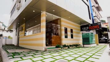 Um hotel com fachada moderna, entrada coberta e uma placa indicando 'ABAB ROOMS' para suítes.