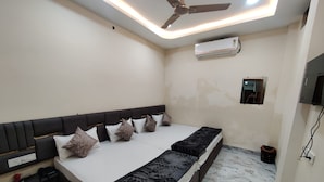 Quarto moderno com uma cama grande, ventilador de teto, ar condicionado e um pequeno espelho na parede.