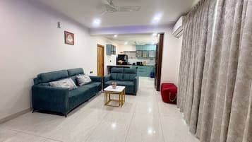 Sala de estar com sofá, mesa de centro e cozinha ao fundo.
