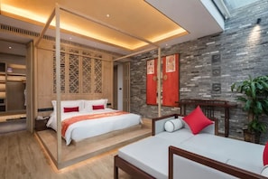 Quarto de hotel moderno com cama, sofá e decoração na parede.