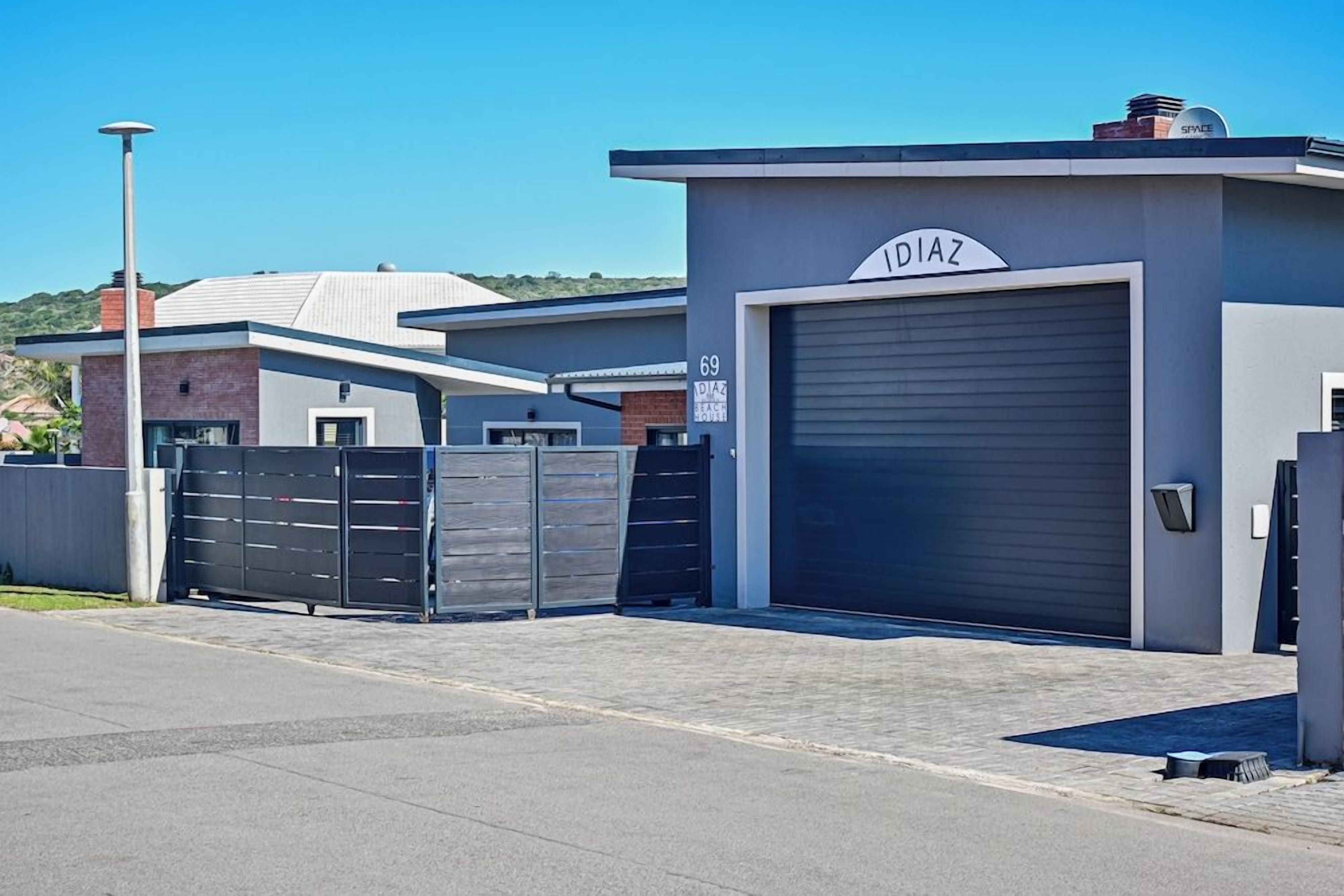 Um edifício moderno com uma porta de garagem identificada com 'DIAZ' e uma entrada com portão.