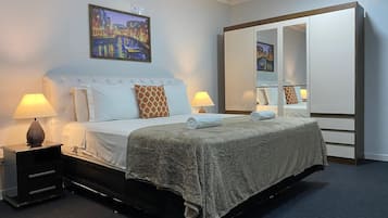 Quarto de hotel com uma cama, duas mesas de cabeceira com abajures, um espelho grande e um quadro na parede.