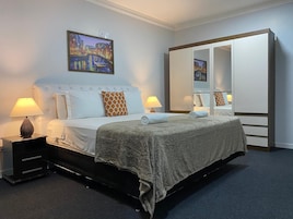 Quarto de hotel com uma cama, duas mesas de cabeceira com abajures, um espelho grande e um quadro na parede.