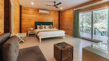 Quarto com painéis de madeira, uma cama, um sofá, uma mesinha e uma mesa de centro de vidro.