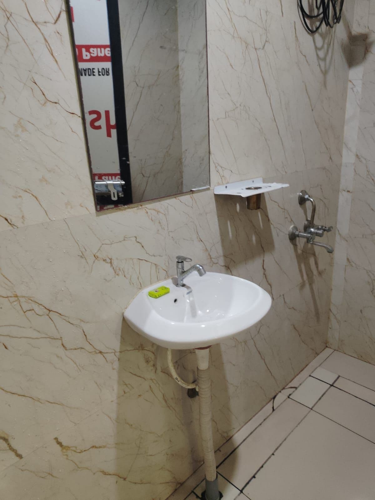 Casa de banho com lavatório branco, espelho e chuveiro.