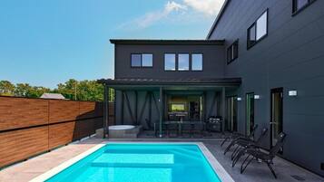 Uma casa moderna com piscina, área de estar externa e um espaço coberto de varanda.