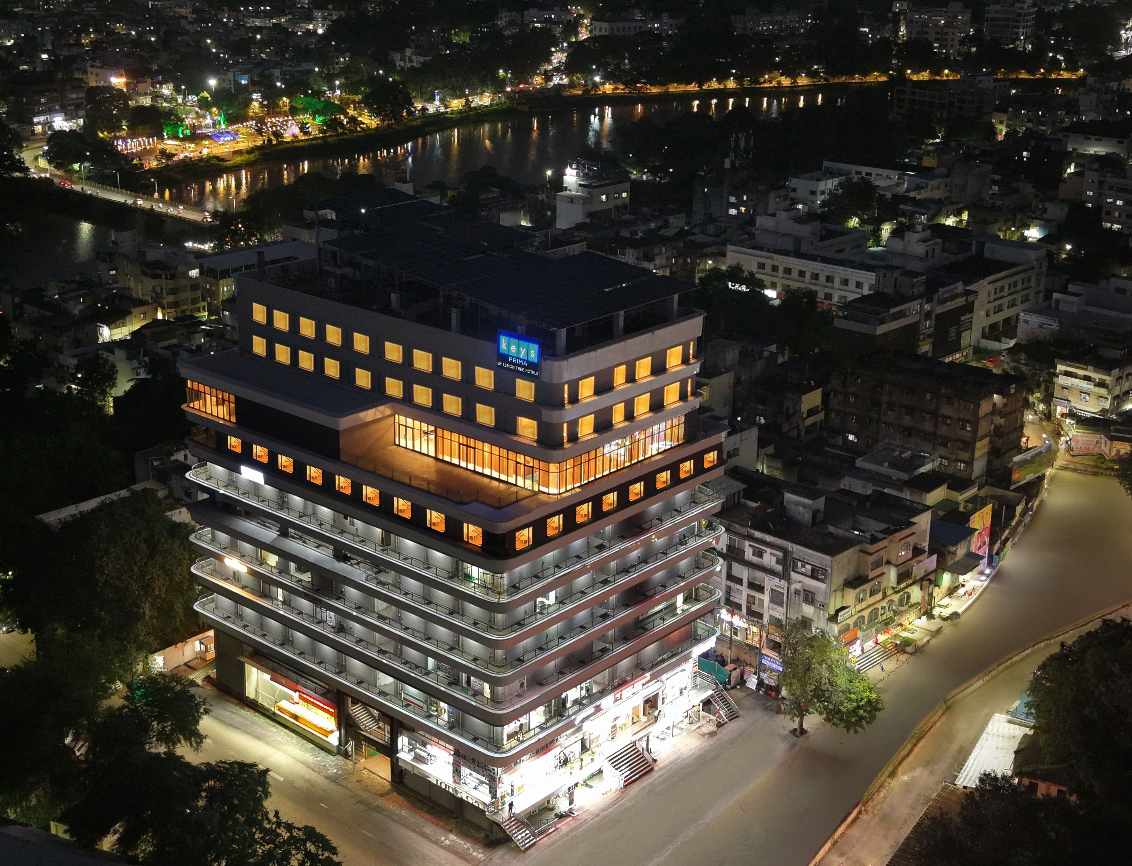 Um hotel com vários andares e design moderno, com entrada destacada, várias varandas e vista para o rio.