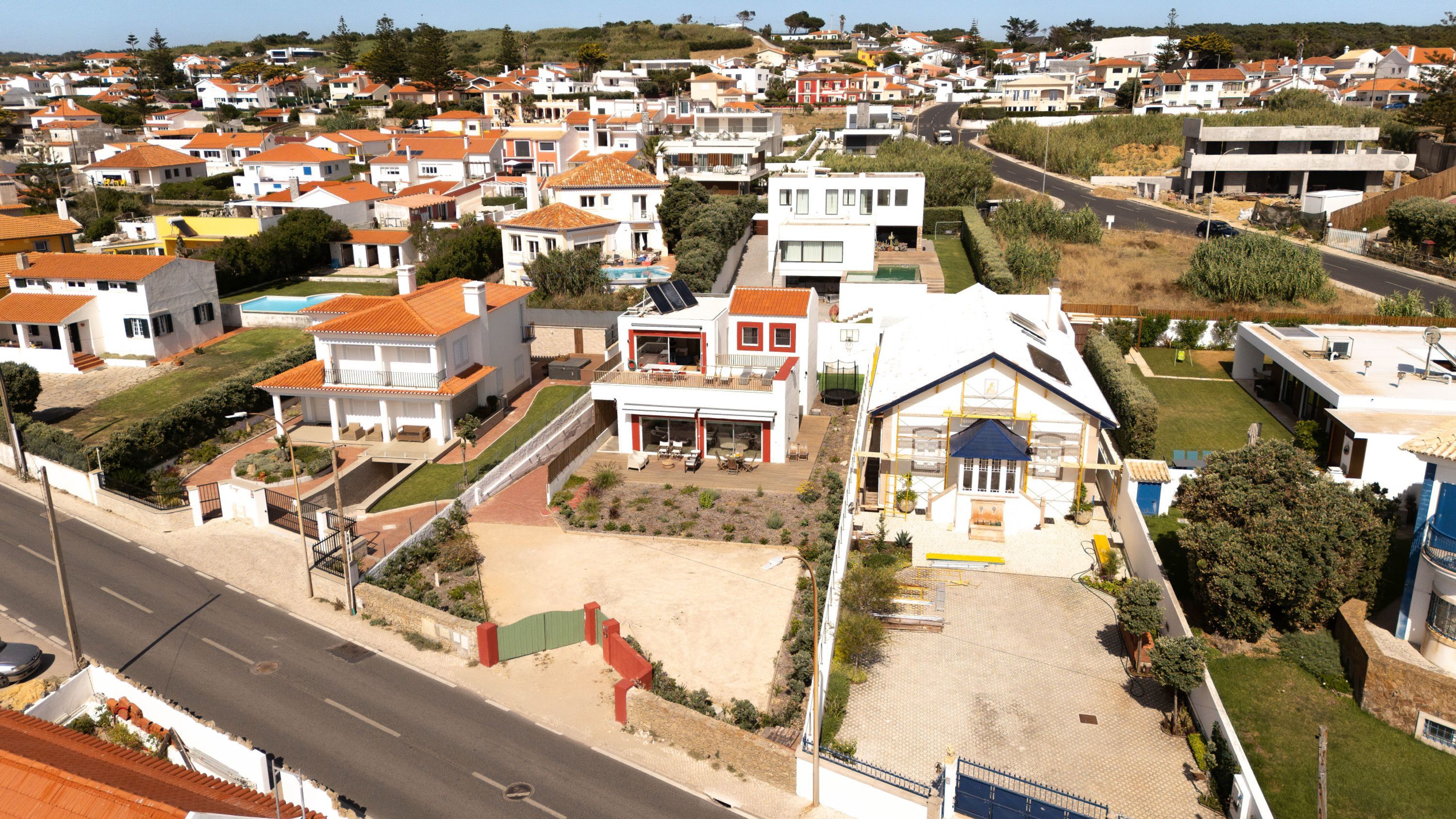 Área residencial com várias casas, uma rua principal e um amplo espaço aberto em primeiro plano.