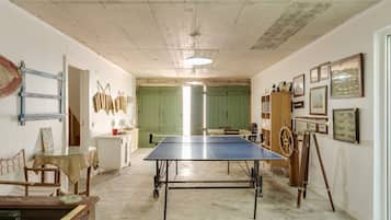 Um quarto com mesa de pingue-pongue, um armário de madeira e diversas fotos emolduradas nas paredes.