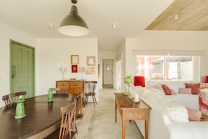 Uma sala de estar ampla com uma mesa de jantar, cadeiras, sofá e teto de madeira.
