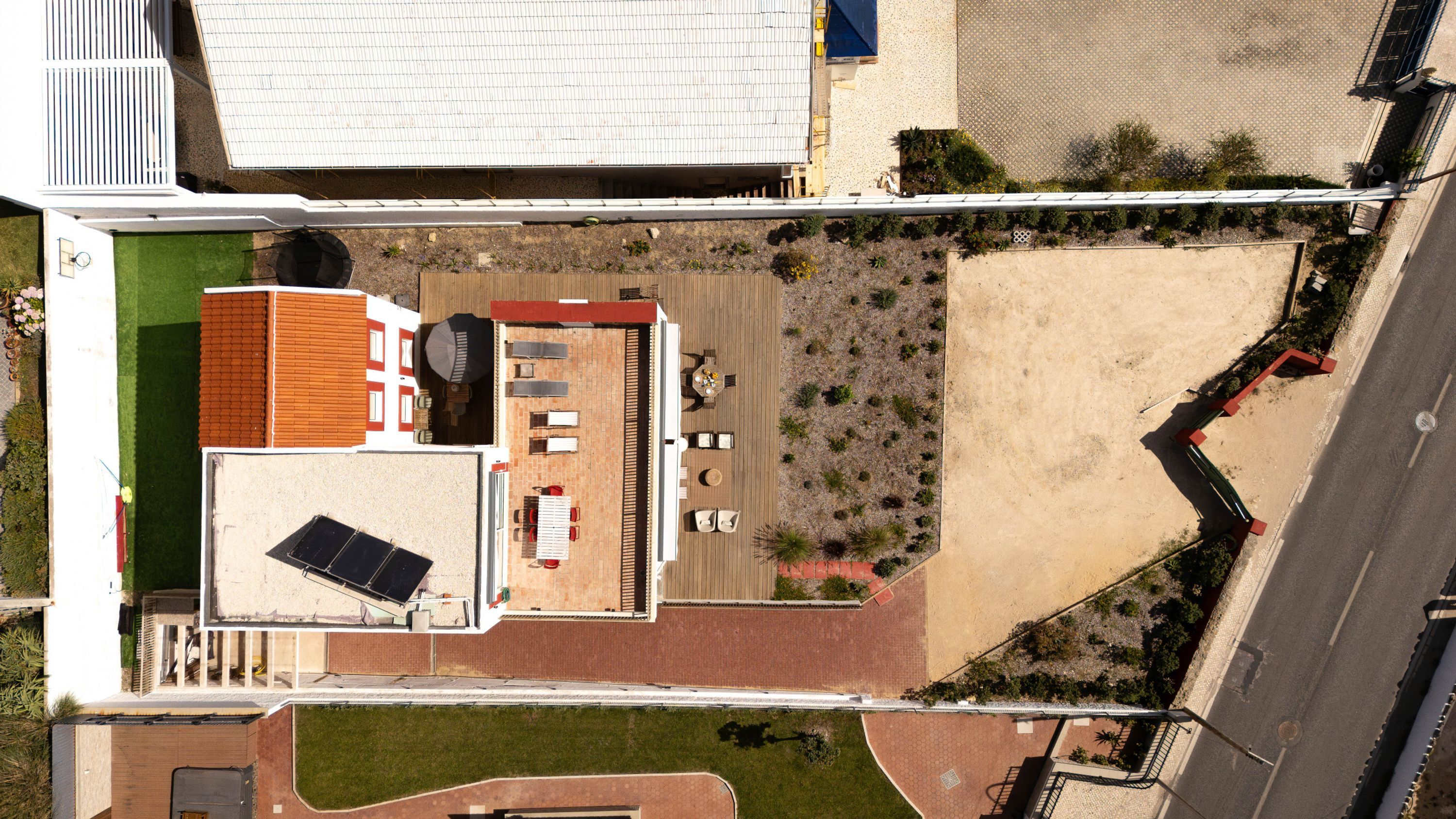 Vista aérea de um hotel com terraço no telhado, piscina e jardim paisagístico.