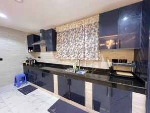 Uma cozinha moderna com armários pretos, bancada preta e cortina estampada.