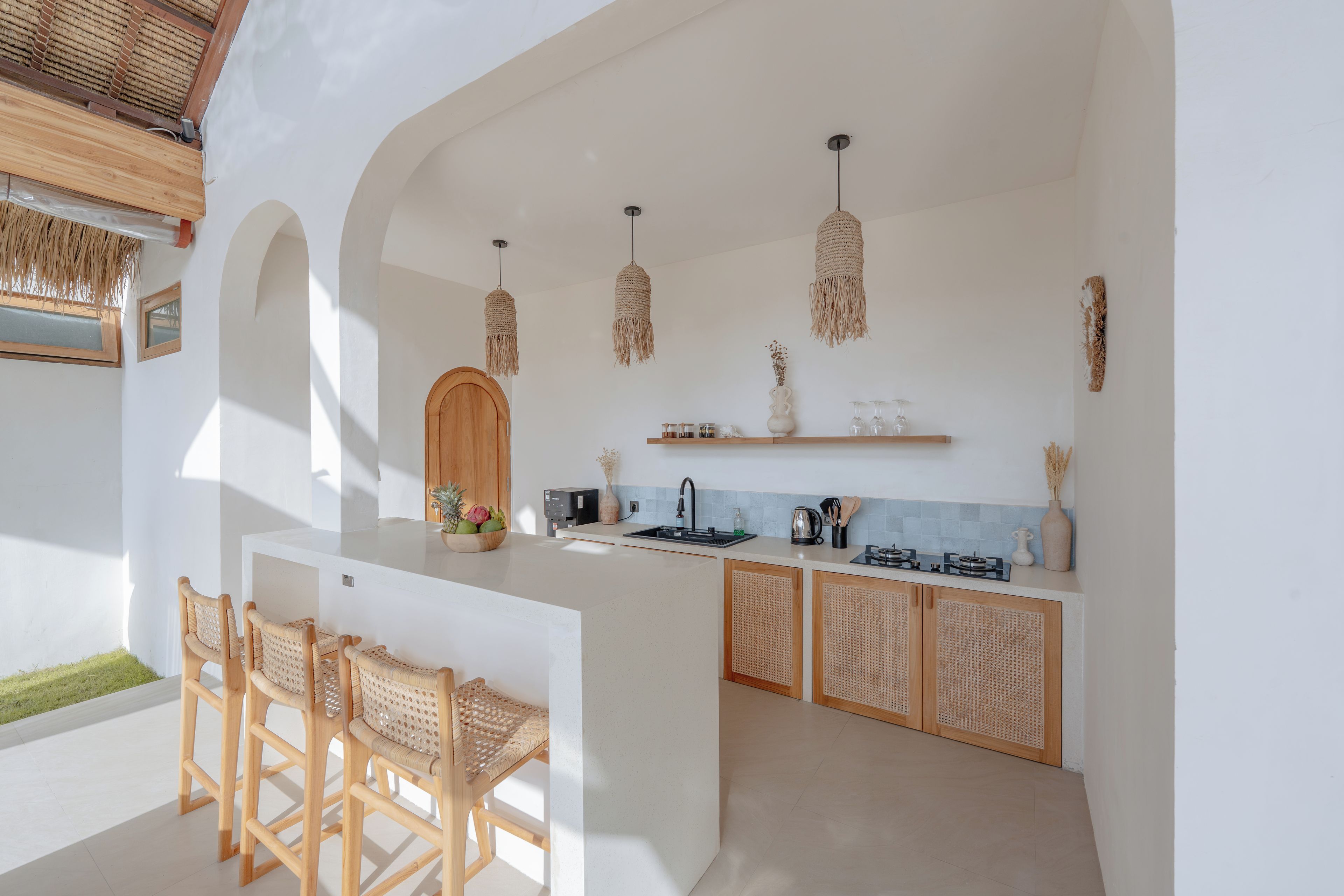 Cozinha moderna com ilha central, cadeiras de madeira e área de refeições.