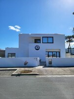 Um edifício moderno com telhado plano, uma pequena entrada e uma placa com um logotipo.