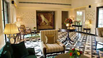 Um hall de hotel com piso quadriculado, um mural grande de tigre e uma área de estar com sofá e poltronas.
