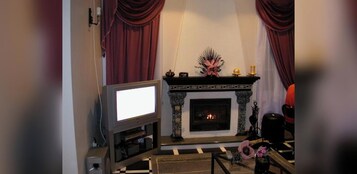 Uma sala de estar com lareira, televisão e piso xadrez.