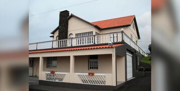 Um edifício de dois andares com varanda, garagem e chaminé.