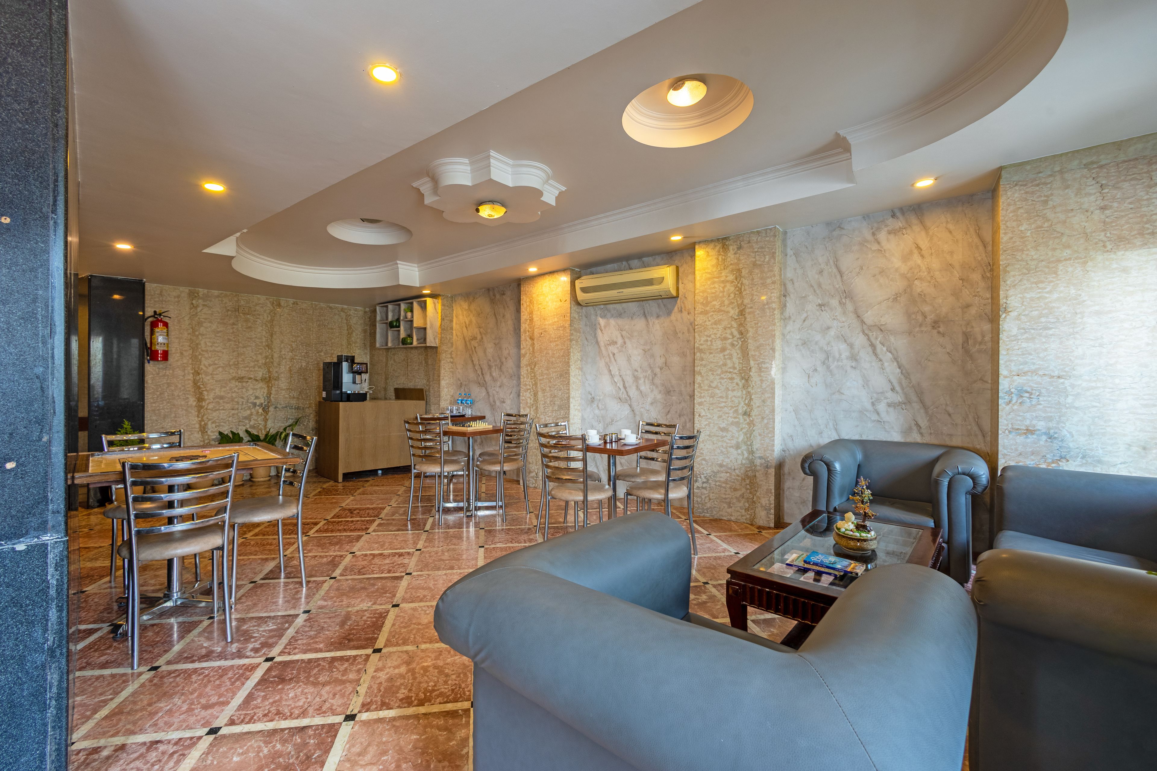 Um saguão de hotel com paredes de mármore, uma estação de café e áreas de estar.