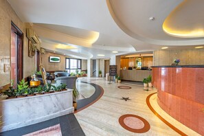 Um hall de hotel com balcão de recepção, área de estar e uma grande janela.