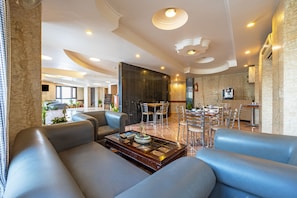 Um hall amplo com área de estar, balcão de recepção e espaço para refeições.
