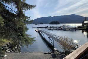 Um lago tranquilo com um píer que se estende sobre a água, rodeado por montanhas e árvores.
