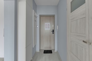 Um corredor com uma porta de madeira, um porta-roupas e um tapete preto na entrada.
