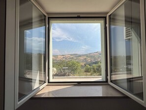 Quarto com uma grande janela e vista para uma paisagem montanhosa.