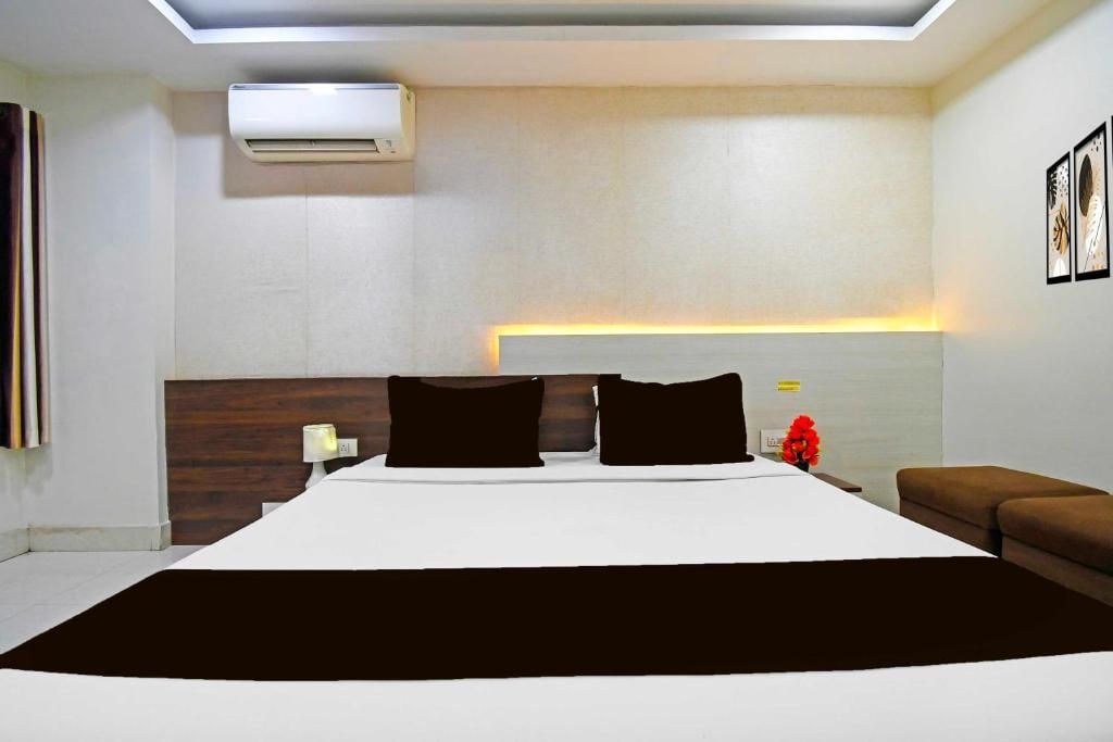 Quarto de hotel com cama, mesa de cabeceira, luminária e ar condicionado.