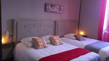 Quarto de hotel com duas camas, cabeceira estofada, um quadro na parede e abajur.