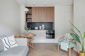 Cozinha compacta com eletrodomésticos modernos, área de jantar com mesa redonda e disposição de assentos com duas cadeiras.