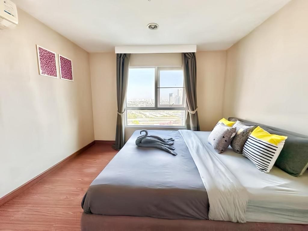 Quarto de hotel com cama, janela com cortinas e vista para a paisagem urbana.
