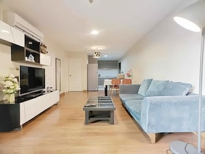 Uma sala de estar moderna com televisão de tela plana, uma mesa de centro e um sofá.
