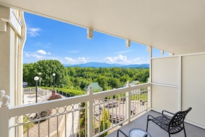Uma varanda com vista para uma área ajardinada e montanhas ao longe.