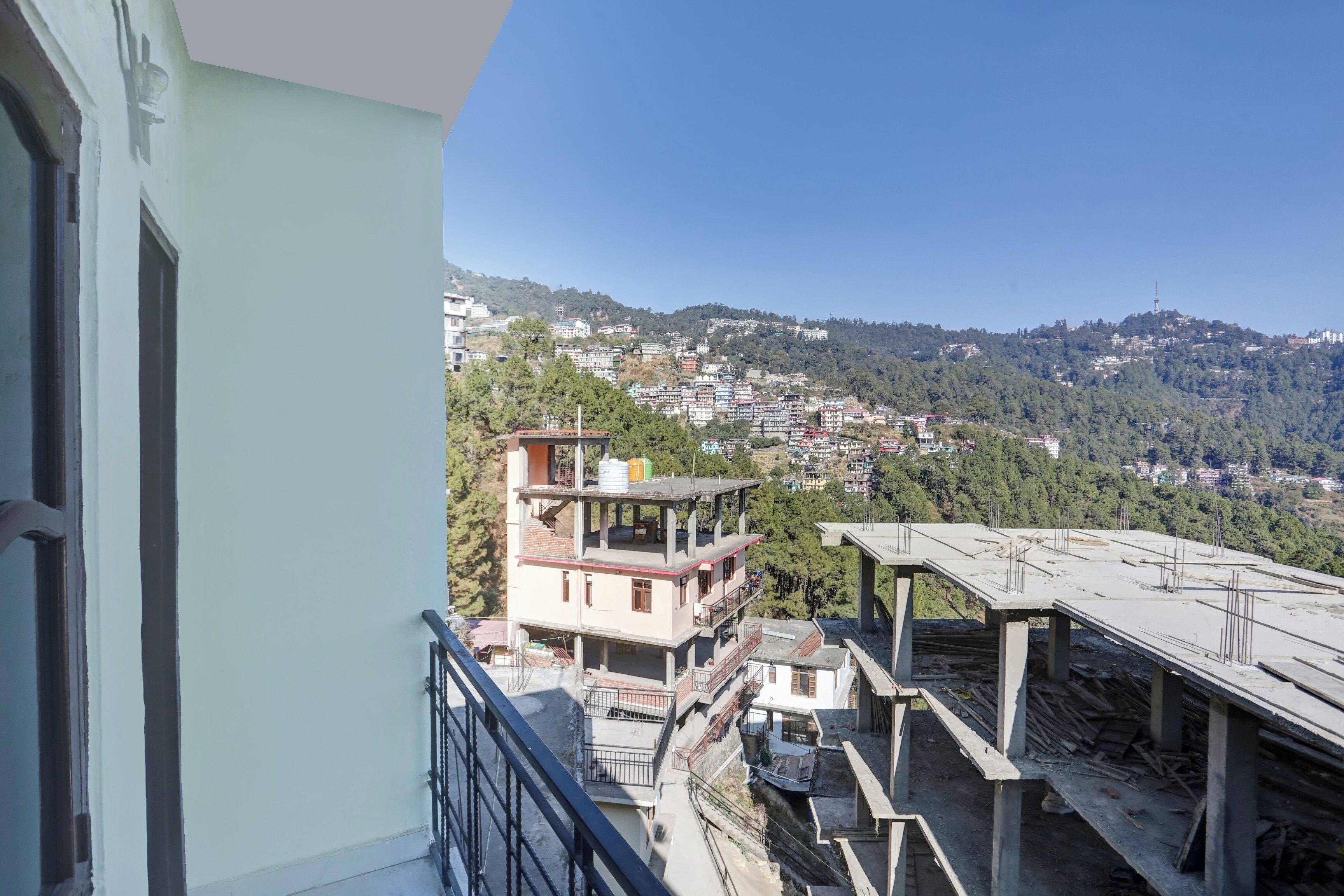 Área residencial com edifícios altos, céu claro e paisagem montanhosa ao fundo.