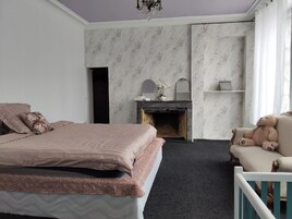 Quarto com cama, cômoda, espelho, lareira e um urso de pelúcia.