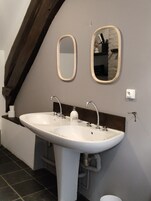 Casa de banho com lavatório duplo, duas espelhas e porta-toalhas.