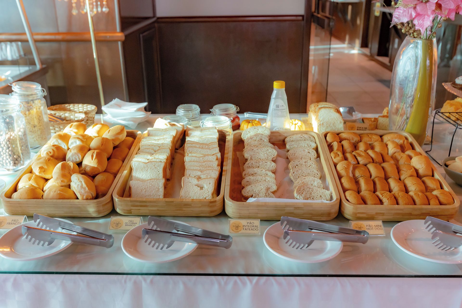 Buffet com diversas opções de pão e utensílios.